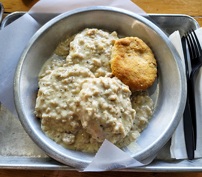 Behold the golden standard of biscuits and gravy &ndash; fluffy buttermilk perfection swimming in creamy, sausage-studded heaven.