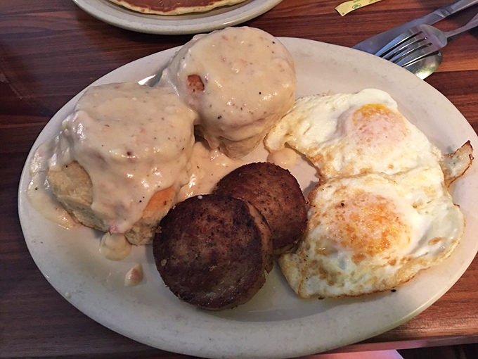 Behold the holy trinity of breakfast: biscuits drowning in peppery gravy, perfectly seasoned sausage, and eggs that belong in the sunshine hall of fame.