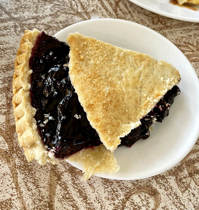 This blueberry pie isn't just dessert, it's a purple-stained declaration that some traditions, like perfect flaky crust, need absolutely no improving.