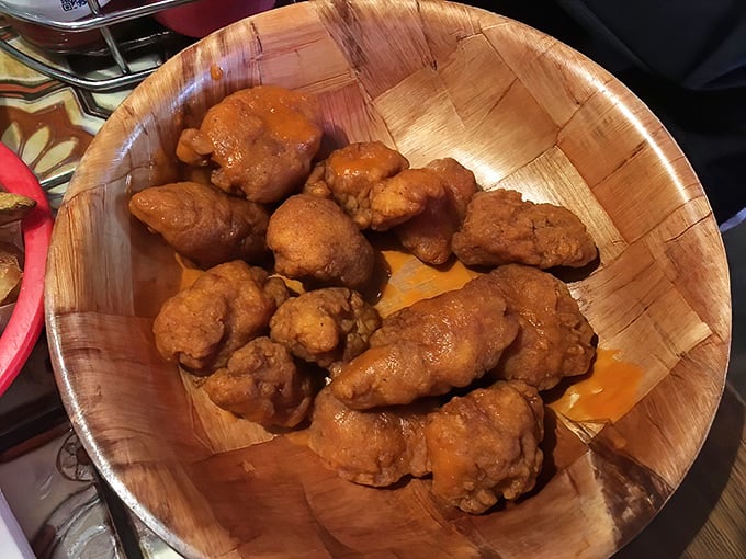 Golden-fried boneless wings glisten with sauce in their wooden bowl, like delicious nuggets of gold waiting to be discovered by hungry prospectors.