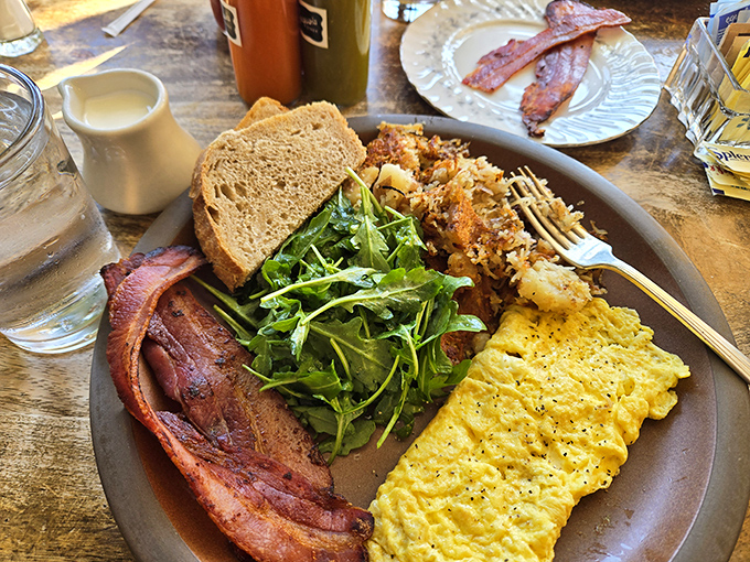 This isn't just breakfast; it's a masterclass in morning perfection featuring eggs, bacon, greens, and artisanal bread harmony.