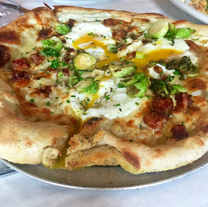 The legendary breakfast pizza in all its glory. Those sunny-side-up eggs create a natural sauce that mingles with pancetta and sausage like they're old friends at a reunion.