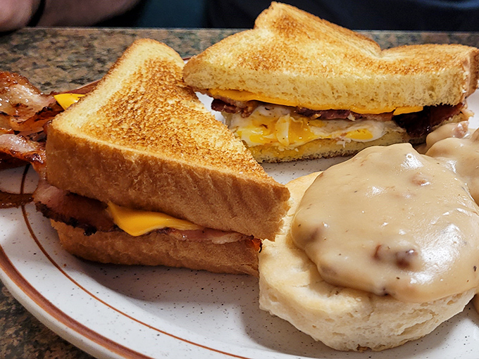 This isn't just a breakfast sandwich; it's morning comfort architecture – golden toast, melty cheese, and that biscuit with gravy? The foundation of a perfect day.