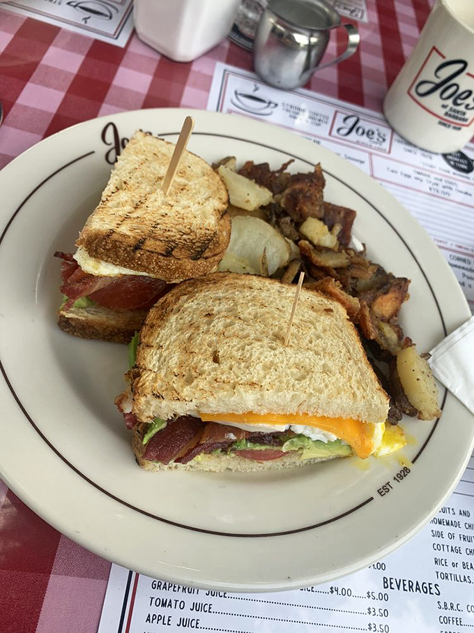 Breakfast sandwich perfection: toasted bread, melty cheese, crispy bacon, and a sunny egg that's basically wearing a halo. Those sides aren't slouching either.
