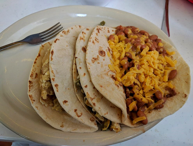 Breakfast tacos that could feed a small village arrive with melted cheese cascading over beans and eggs like a yellow waterfall of joy.