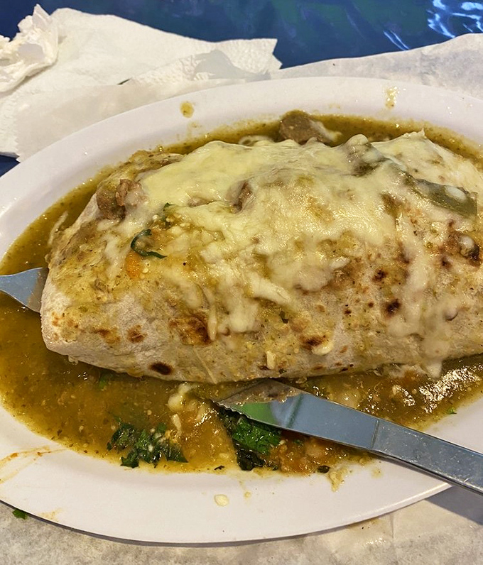 Behold the wet burrito of your dreams—cheese melted to perfection, swimming in a consommé that deserves its own Grammy for composing such harmonious flavors.