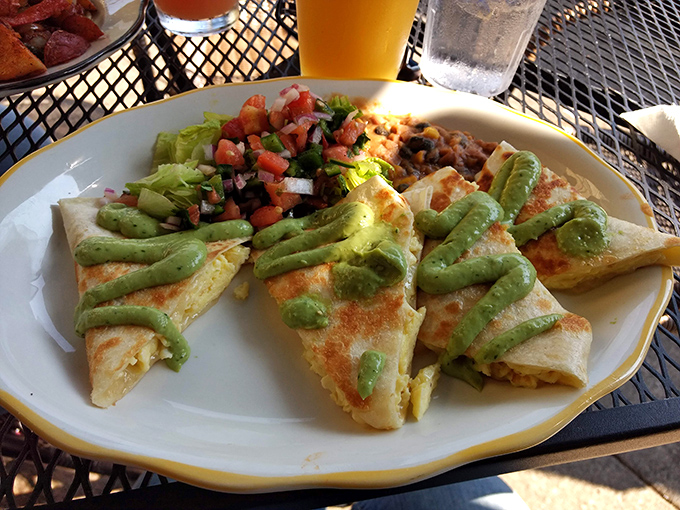 The breakfast quesadilla&mdash;where tortilla meets morning magic. Those green avocado drizzles aren't just garnish; they're little highways to flavor town.