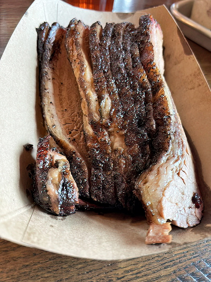 Behold the brisket in all its bark-encrusted glory &ndash; each slice bearing that coveted pink smoke ring that separates barbecue artistry from mere cooking.