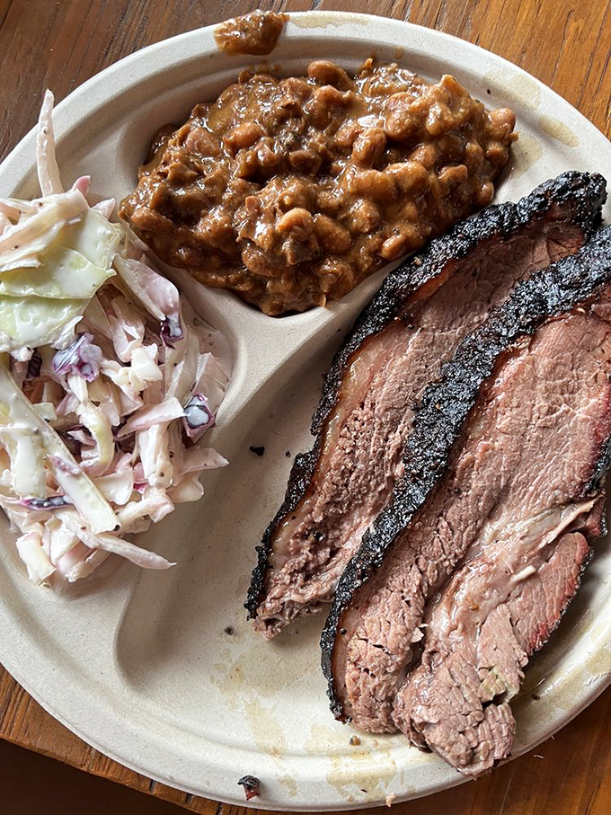 Brisket with that textbook smoke ring sitting alongside creamy slaw and beans—this plate is basically the barbecue equivalent of winning the lottery.
