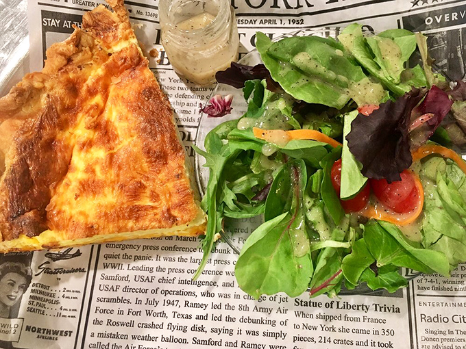 A golden triangle of quiche perfection alongside a garden-fresh salad&mdash;proof that vegetables are just pie's responsible chaperones.