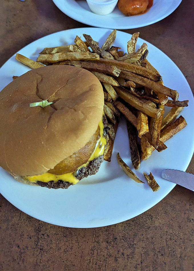 Behold the star of our show: a perfectly proportioned cheeseburger with hand-cut fries that would make fast food chains weep with inadequacy.