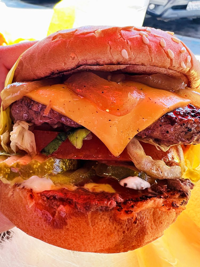 Architecture of indulgence: melted cheese cascades down a perfectly charred patty while fresh veggies provide the illusion of nutritional balance.