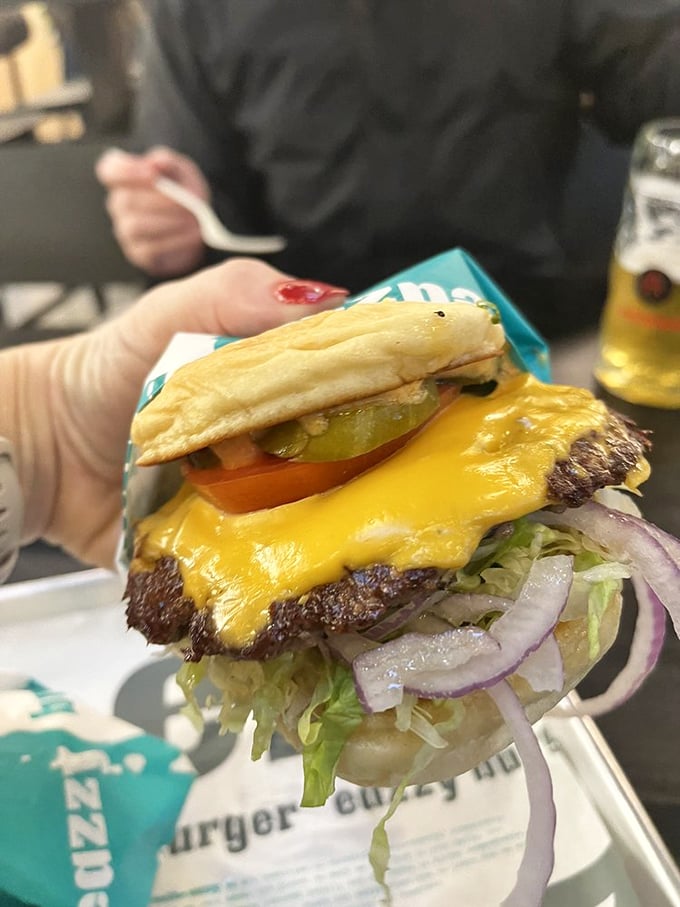 Behold the perfect burger architecture: golden cheese cascading over a perfectly cooked patty like edible lava meeting lettuce paradise.