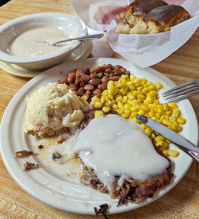 This chicken fried steak isn't just covered in gravy &ndash; it's swimming in a creamy ocean of Southern comfort with corn and beans standing guard.