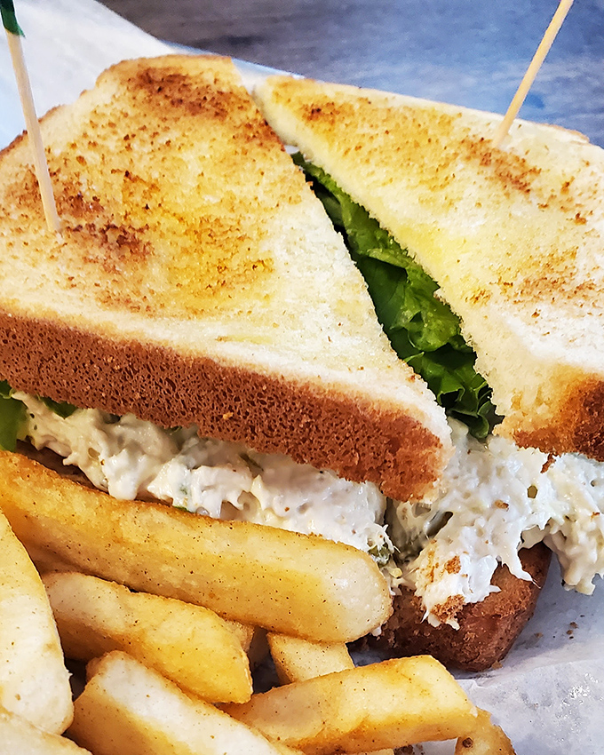 The legendary chicken salad sandwich arrives with golden fries, a mountain of creamy goodness between perfectly toasted bread that makes you wonder why you'd eat anything else. 