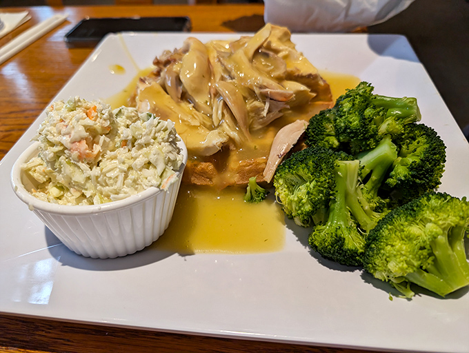 Tender chicken smothered in gravy alongside fresh broccoli and homemade coleslaw – proof that balance in a meal is possible after all.