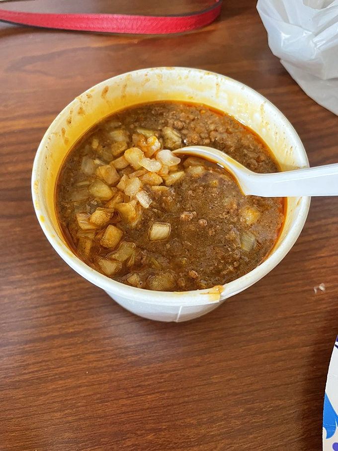 Cincinnati chili in its natural habitat&mdash;a simple bowl showcasing that distinctive sauce-like consistency with diced onions playing supporting roles.