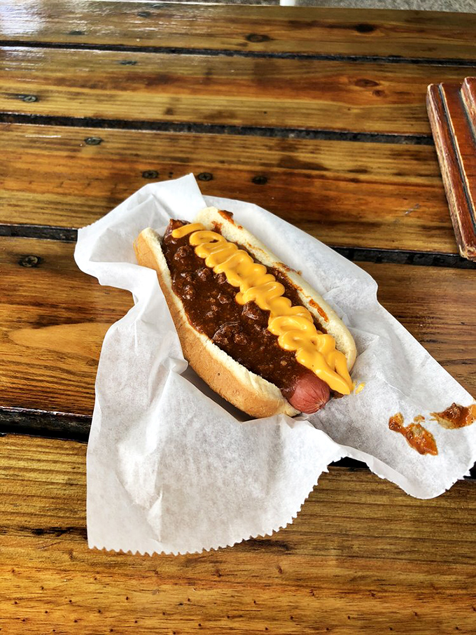 Behold the holy grail of comfort food: a chili dog with mustard zigzagged like modern art, nestled in paper that's soon to become a souvenir.