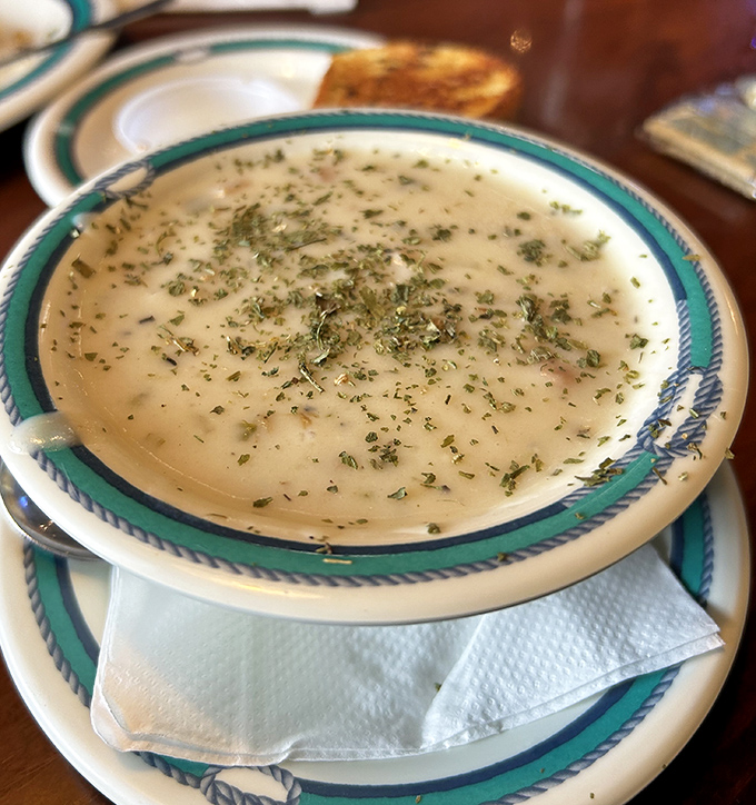 The legendary clam chowder arrives like a creamy ocean whisper, herbs dancing on the surface, promising comfort in every spoonful.