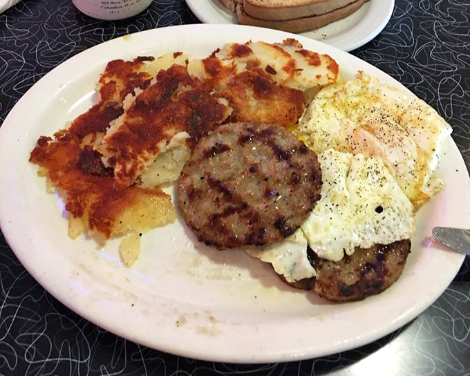Breakfast perfection on a plate: crispy hash browns, savory sausage patties, and eggs that would make a chicken proud.