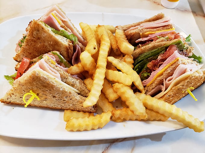 The club sandwich: architectural marvel of the culinary world. Those perfectly golden crinkle-cut fries aren't just sides&mdash;they're supporting actors deserving their own award.