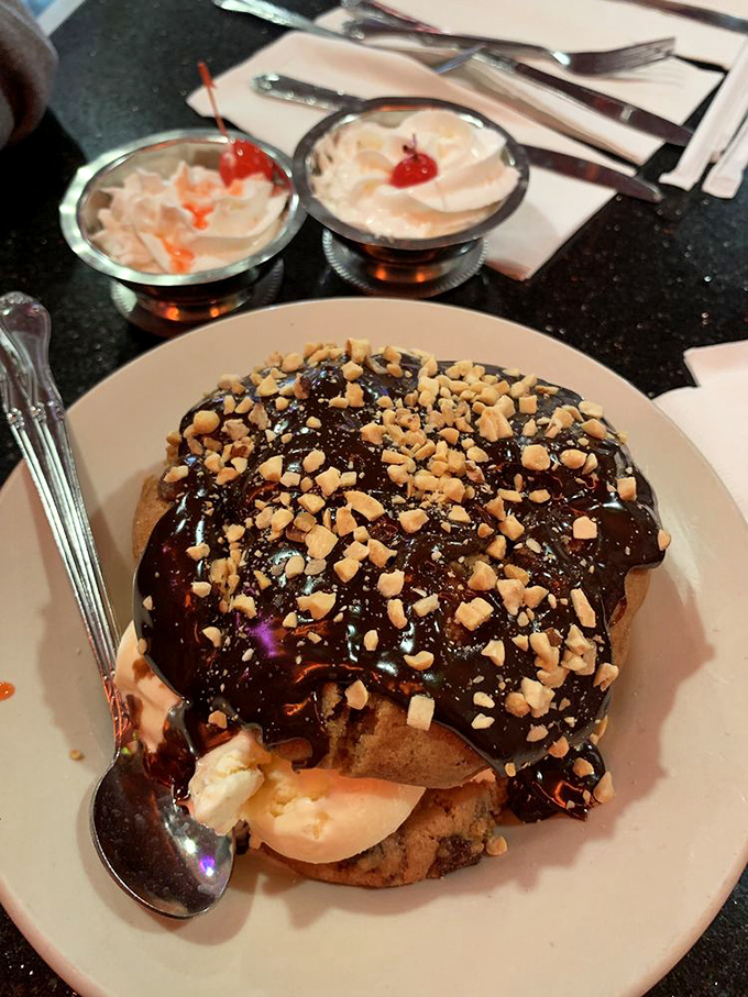 This isn't just dessert, it's architecture. A cookie foundation supporting ice cream, hot fudge, and enough nuts to make a squirrel retire early.
