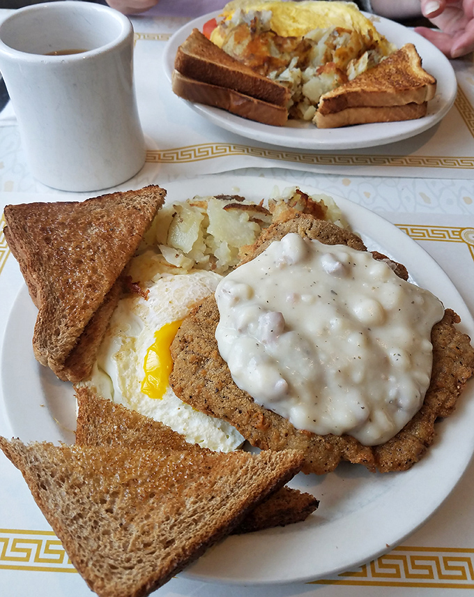 Behold the holy trinity of diner perfection: golden-crisp country fried steak smothered in pepper gravy, a sunny-side-up egg, and toast standing by for yolk-sopping duty.