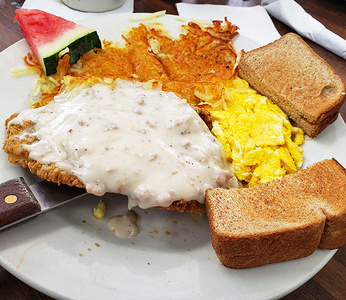 Country fried steak smothered in gravy alongside golden hash browns and scrambled eggs &ndash; the breakfast trinity that launched a thousand naps.