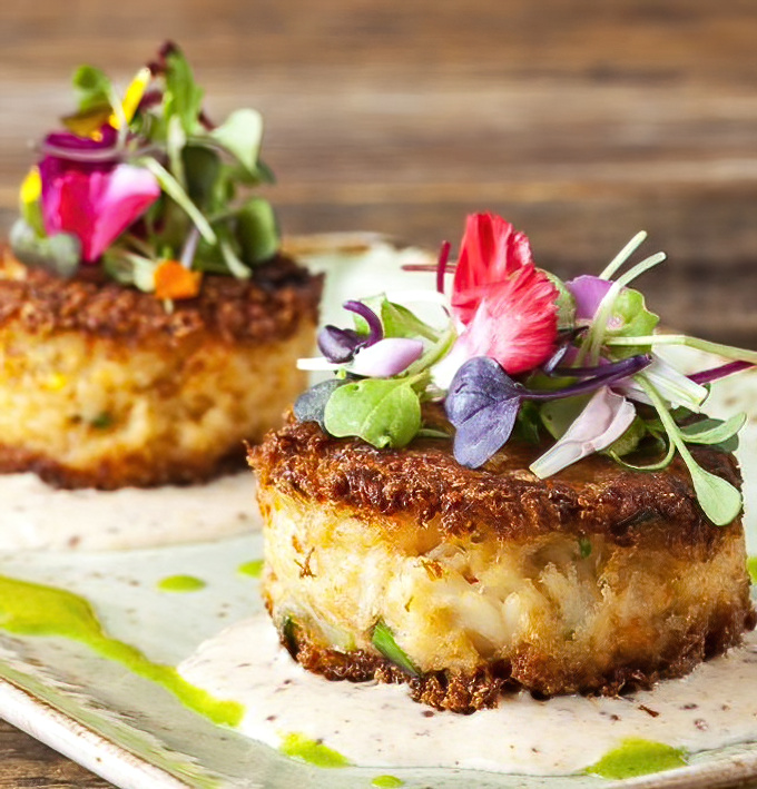 Golden-brown crab cakes that make you want to write poetry: minimal filler, maximum flavor, topped with delicate microgreens.