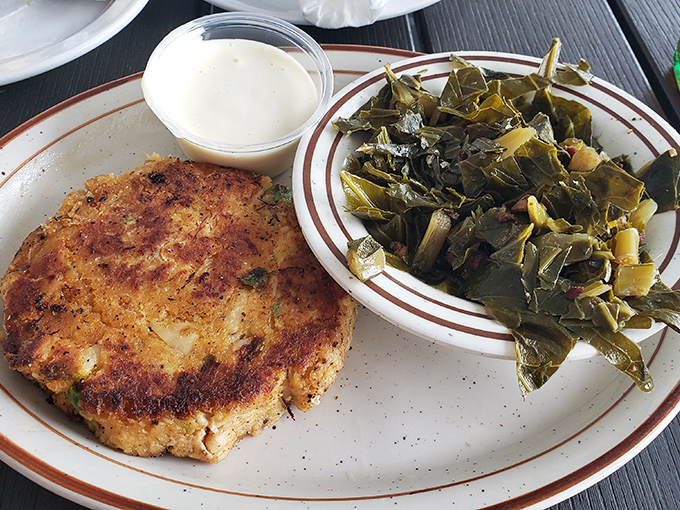 This isn't just any crab cake; it's a golden-brown masterpiece with minimal filler and maximum flavor, paired with Southern-style collards. 