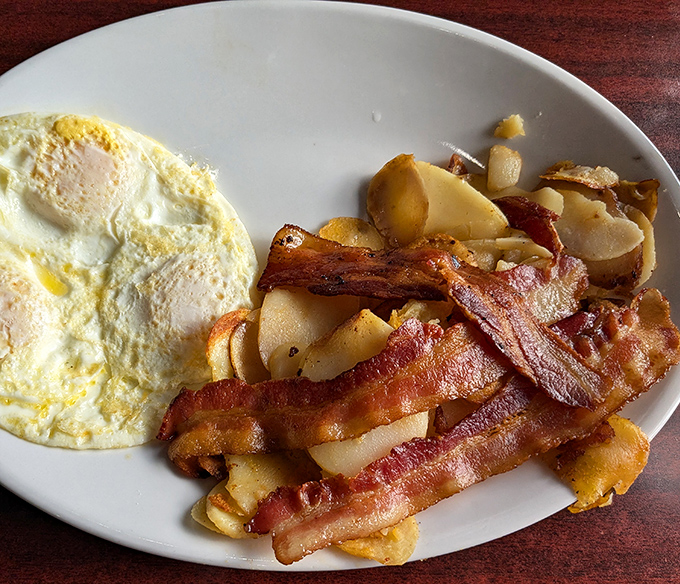 Breakfast perfection on a plate: eggs cooked just right, bacon with that ideal crisp-to-chewy ratio, and home fries that could make a potato proud.