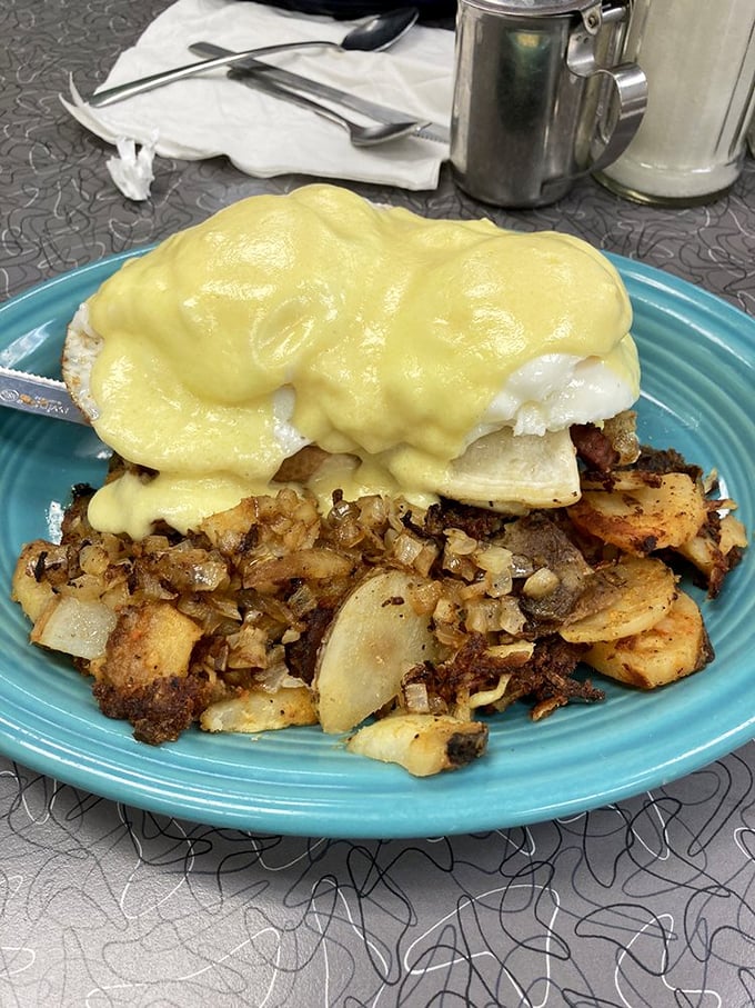 Behold the holy grail of breakfast &ndash; Eggs Benedict with hollandaise cascading like a golden waterfall over perfectly poached eggs and crispy home fries.