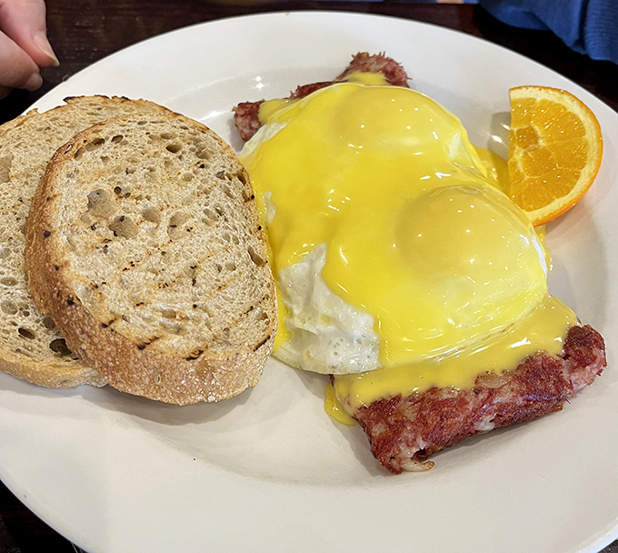 Hollandaise sauce cascading over eggs Benedict like a golden waterfall of morning joy. Breakfast architecture at its finest.