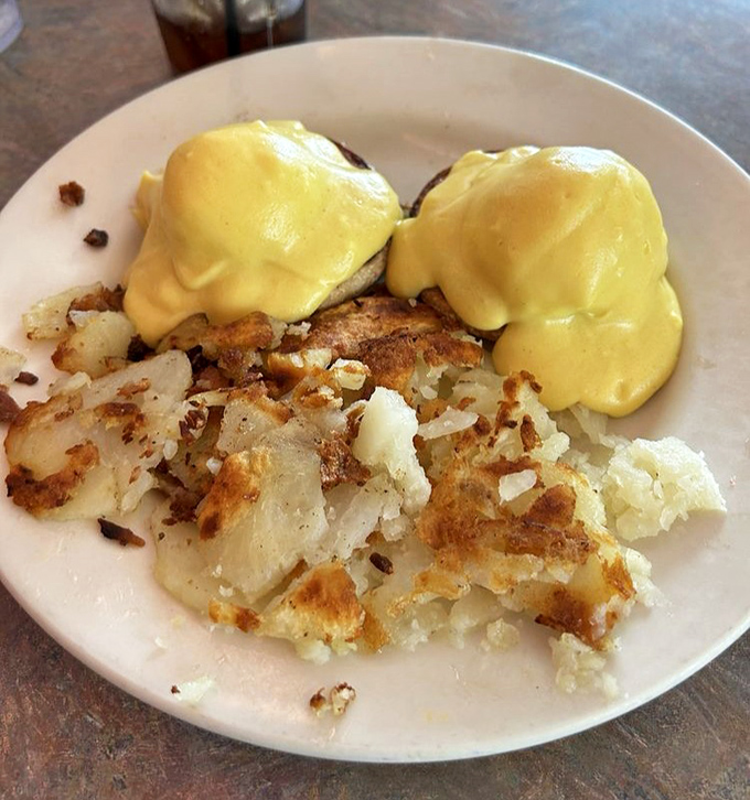Eggs Benedict done diner-style&mdash;a golden hollandaise waterfall cascading over English muffins, with home fries crisped to that perfect sweet spot between tender and crunchy.