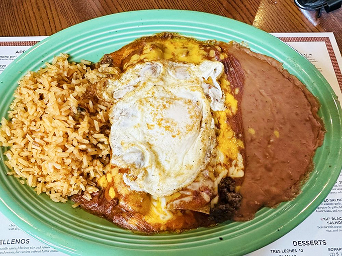 Behold the star of the show: enchiladas topped with a perfectly fried egg, flanked by Spanish rice and refried beans. Comfort food royalty.