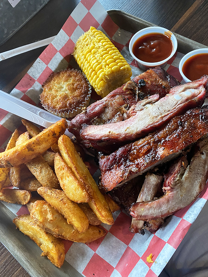 Behold the holy trinity of barbecue bliss: perfectly smoked ribs with that telltale pink smoke ring, crispy fries, and corn on the cob to round out the experience.