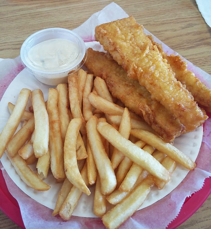 Golden perfection on a plate. This fish is wearing a crispy coat more impressive than anything in the Royal wardrobe, with chips standing at attention like the Queen's Guard.