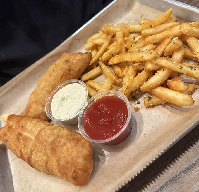 The legendary fish and chips&mdash;golden, crispy batter hugging flaky white fish alongside hand-cut fries. This isn't bar food; it's edible poetry served on a metal tray.