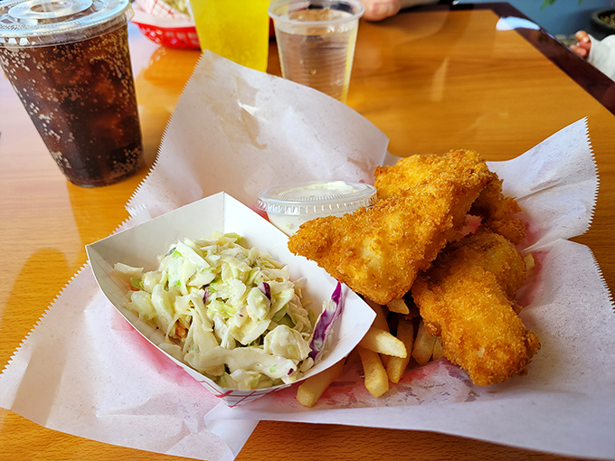 Golden-battered fish that shatters with each bite, nestled alongside crispy fries and creamy coleslaw—the holy trinity of coastal comfort food.