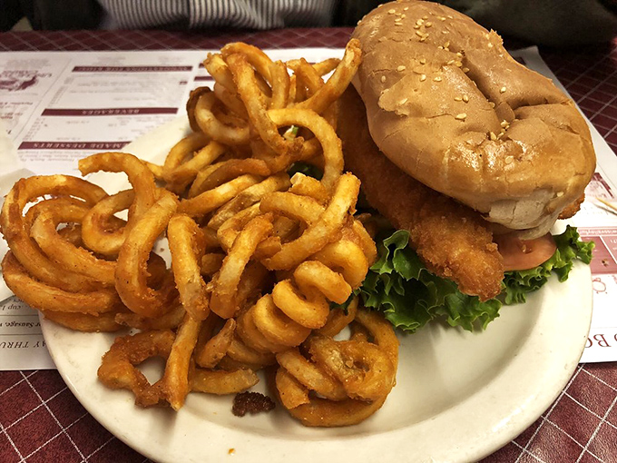 Golden curly fries spiral around a fish sandwich that proves simple ingredients create extraordinary moments.