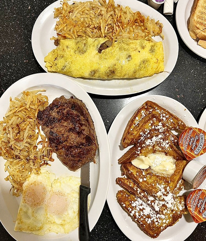 Breakfast symphony in three movements: a fluffy omelet, perfectly seared steak, and French toast dusted with powdered sugar&mdash;the holy trinity of morning indulgence.