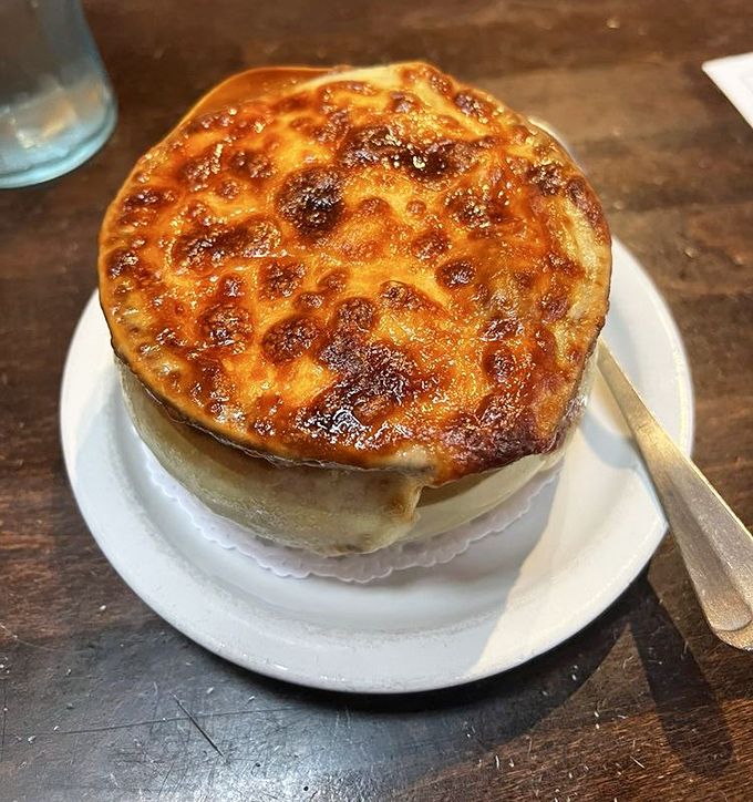 Behold the legendary French onion soup in all its glory &ndash; that perfectly browned cheese canopy hiding a treasure of caramelized onions and rich broth below.