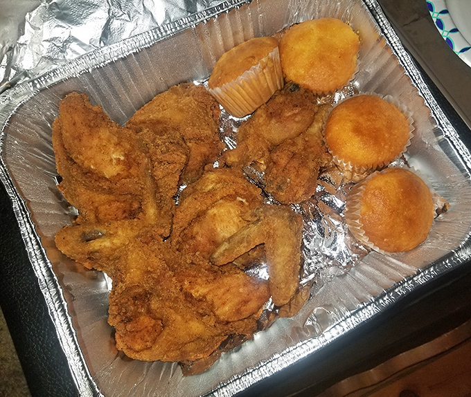 Fried chicken perfection in its natural habitat&mdash;golden-brown, crispy-skinned, and surrounded by those golden cornbread muffins that deserve their own fan club.