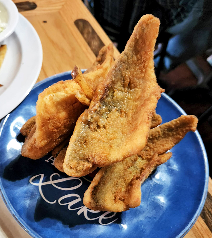 Golden-brown perch fillets stacked like treasure on a blue plate. This isn't just fried fish &ndash; it's Ohio's culinary heritage wearing a perfectly crispy jacket.