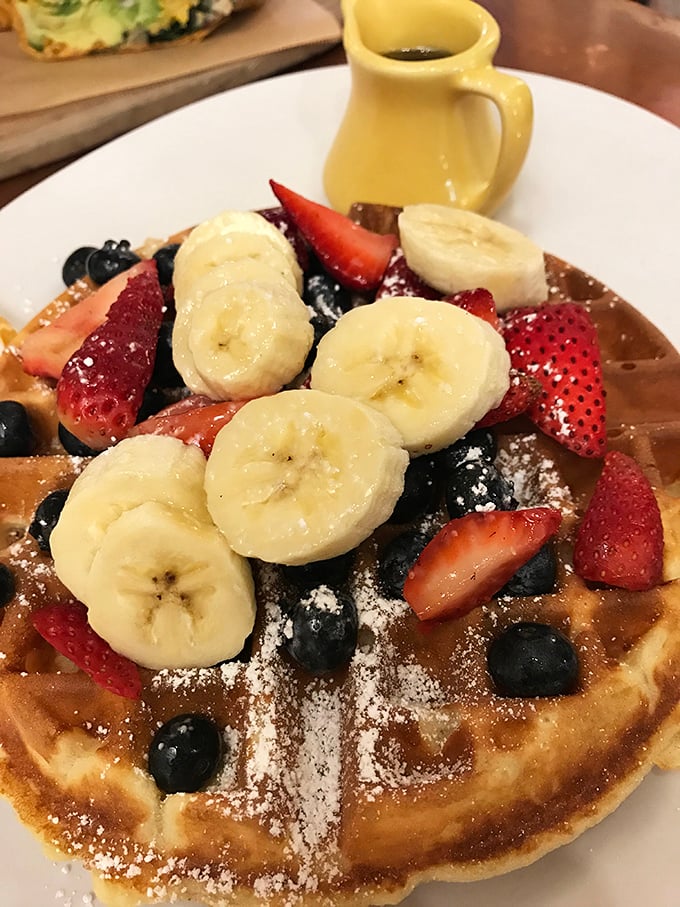 Breakfast nirvana achieved! This waffle doesn't just have fruit on top&mdash;it's practically hosting a berry-banana summit meeting under a gentle snowfall of powdered sugar.