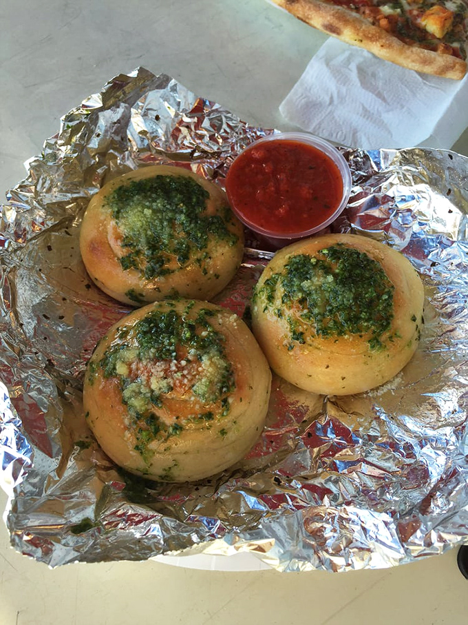 These garlic knots arrive like edible treasures wrapped in foil, demanding immediate attention and reverence.