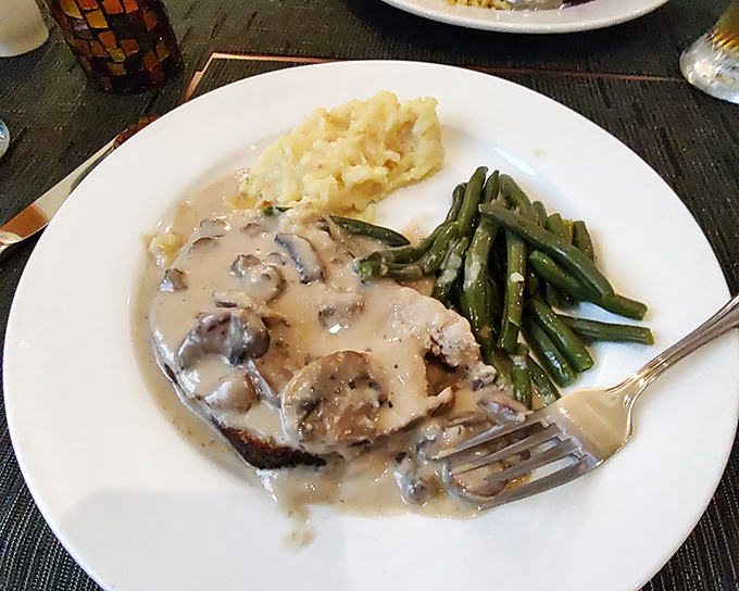 The famous German meatloaf arrives like royalty, draped in mushroom sauce. Those mashed potatoes and green beans aren't just sides&mdash;they're loyal subjects.