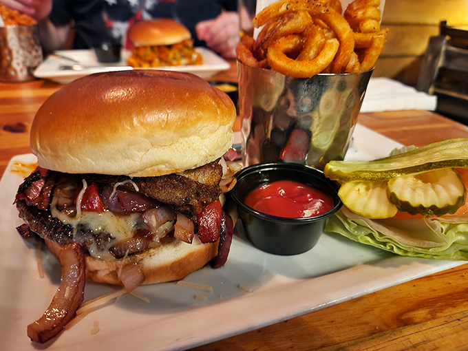 Behold the burger in its natural habitat &ndash; gloriously stacked, perfectly charred, and flanked by golden onion rings that deserve their own fan club.
