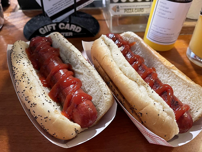 Two perfect hot dogs lounging in their paper boats like sunbathers on a beach. The poppy seed buns cradle their precious cargo with the tenderness of a first love.