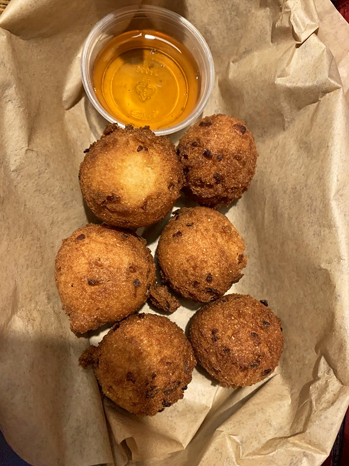 These golden hush puppies aren't just side dishes; they're little orbs of cornmeal perfection that cause temporary table truces when the last one remains.
